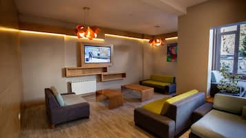 Uma área de lounge moderna com sofás, televisão e piso de madeira.