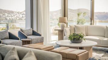 Uma sala de estar moderna com sofá, banquinho e mesa de centro redonda. Há uma luminária e um vaso de planta em uma mesinha lateral.