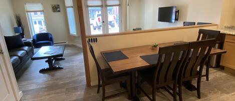 Uma sala de estar ampla com uma mesa e cadeiras de madeira, um sofá e uma televisão.