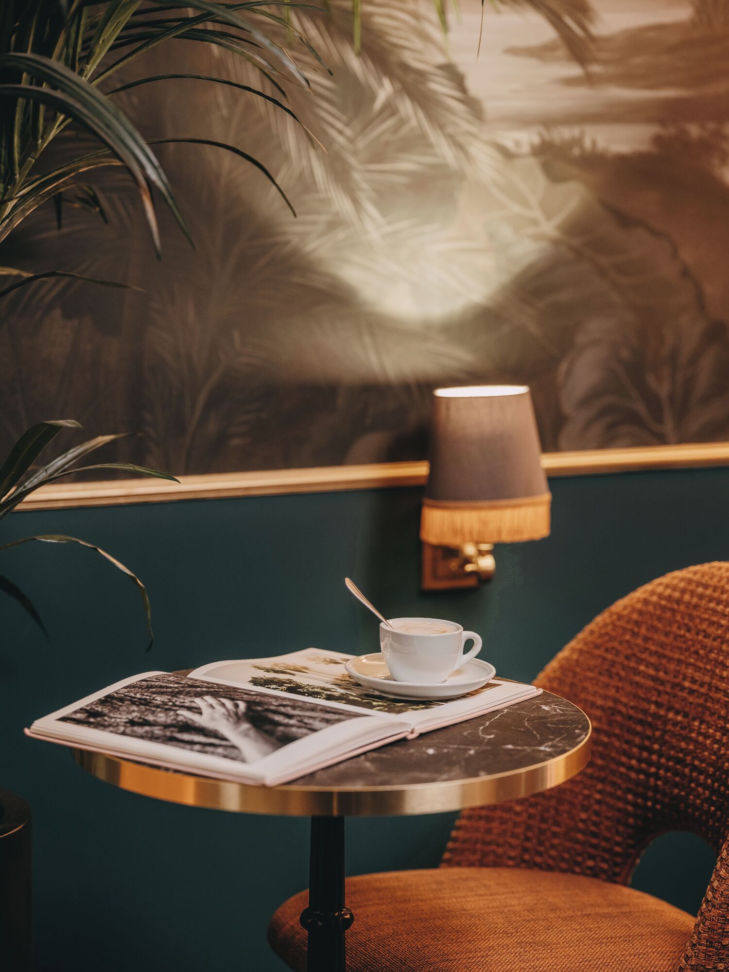 Um cantinho aconchegante para leitura, com uma mesa, uma xícara de café, uma revista e uma luminária.