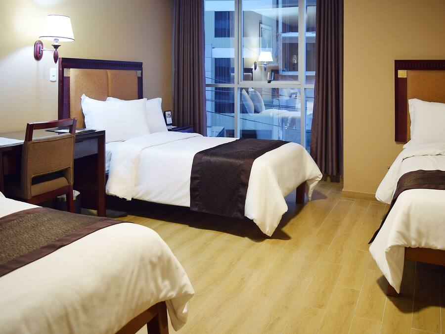 Quarto de hotel com duas camas, uma escrivaninha e uma cadeira.