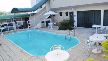 Piscina com escorregador, área de estar externa e escadaria para um nível superior.