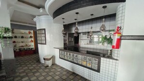 Uma cozinha moderna com paredes revestidas de azulejos brancos, bancada preta e luminárias pendentes.