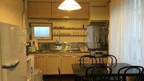 Uma cozinha compacta com geladeira, fogão, pia e uma mesa de jantar com cadeiras.