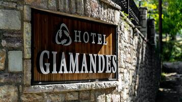Uma placa de madeira com as palavras 'HOTEL GIAMANDES' e um ícone de montanha.