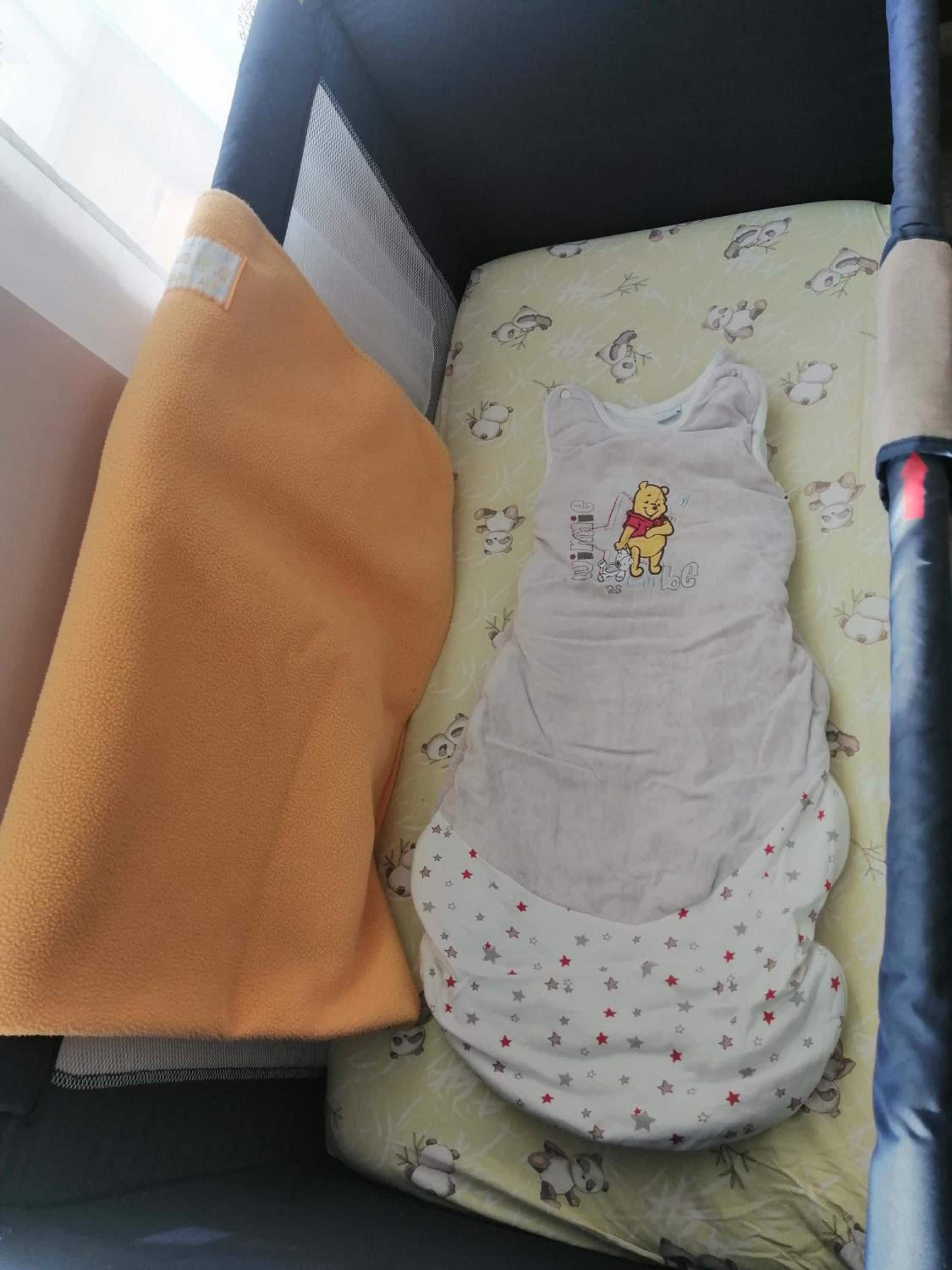 Berço com roupa de bebê e cobertor.