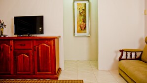 Uma sala de estar com televisão em um armário de madeira, um quadro na parede e um sofá.