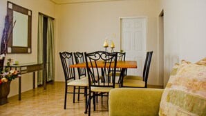 Uma sala de jantar com mesa, cadeiras, um espelho e uma porta.
