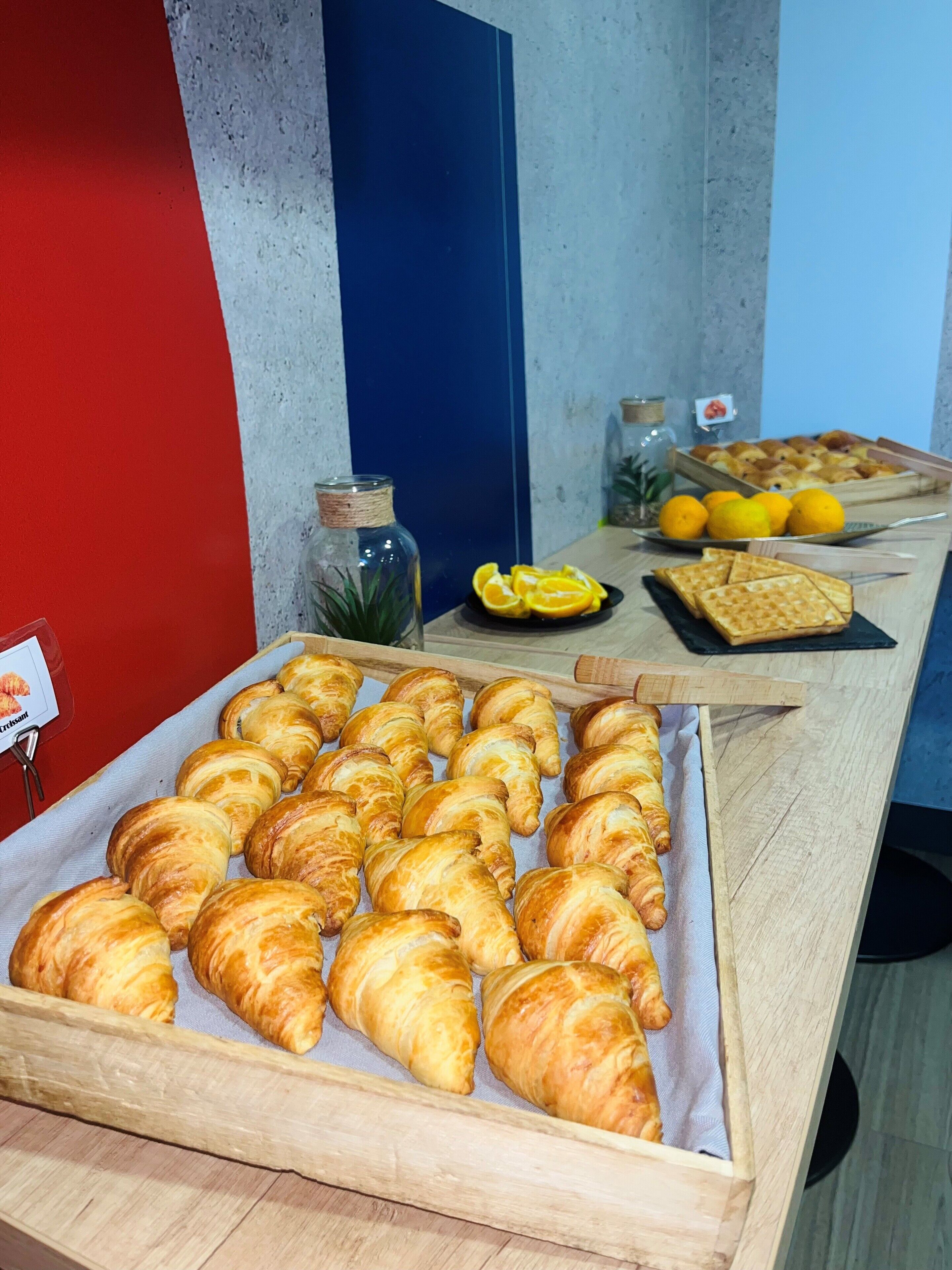 Buffet de café da manhã com croissants, laranjas e outras iguarias.