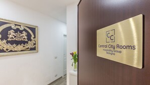 Placa indicando Central City Rooms num corredor com um emblema decorativo na parede.