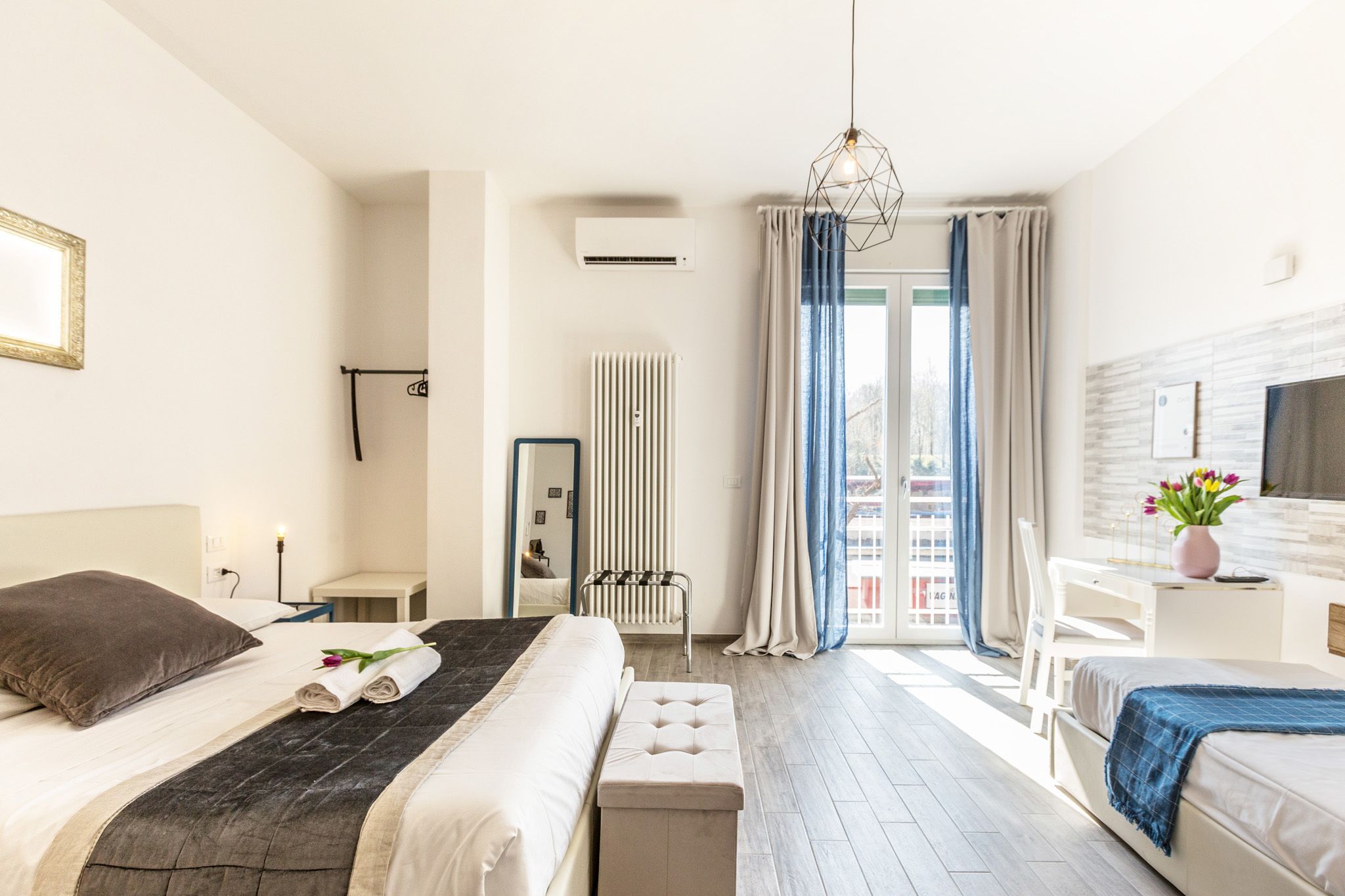 Quarto de hotel moderno com uma cama grande, uma escrivaninha, um espelho e vista para a cidade.