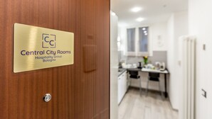 Porta de um quarto de hotel com uma placa indicando que pertence ao Central City Rooms, do Hospitality Group, em Bolonha.