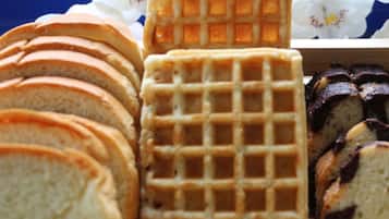 Diversos tipos de pão fatiado e um waffle.
