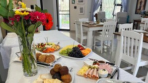 Uma mesa de jantar com diversos tipos de comida e um vaso de flores.