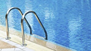 Piscina com guarda-corpos de metal e borda revestida em azulejo.