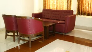 Uma sala de estar com um sofá vermelho, duas poltronas iguais e uma mesa de centro de madeira.