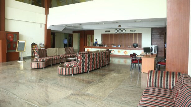 Um lobby espaçoso com balcão de recepção, área de estar e uma grande janela com vista para o lobby.