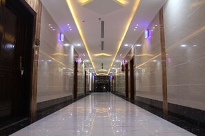 Corredor longo e bem iluminado, com pisos refletivos e luminárias modernas.