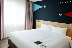 Quarto de hotel com uma cama grande, cabeceira de madeira e parede com decoração de aviões.