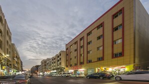 Um hotel com vários andares, fachada em vermelho e amarelo, e algumas lojas no térreo.