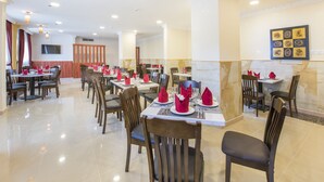 Um restaurante espaçoso com várias mesas e cadeiras, cada conjunto com guardanapos e pratos vermelhos.