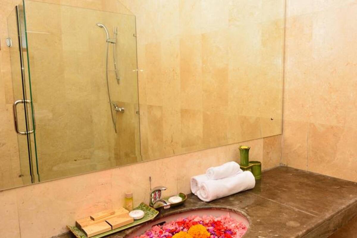 Um banheiro com box de vidro, pia com artigos de higiene pessoal e um arranjo floral decorativo.