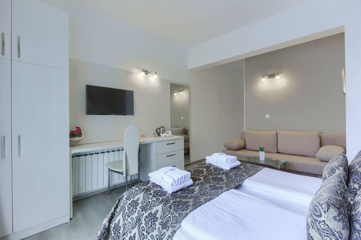 Quarto de hotel moderno com cama, sofá, escrivaninha e cadeira.