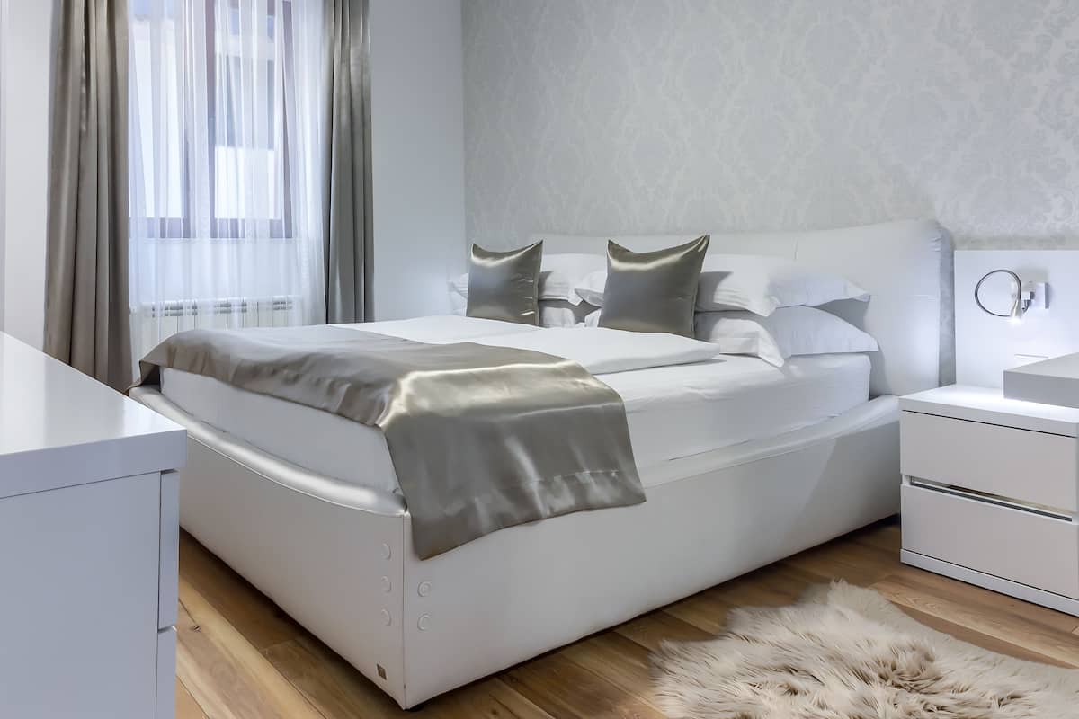 Um quarto moderno com uma cama grande, mesas de cabeceira, um espelho de toucador e um tapete macio.