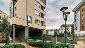 Um edifício de apartamentos moderno com fachada plana, várias varandas e uma placa indicando ser um complexo residencial.