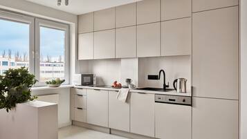 Cozinha moderna com uma janela ampla, armários brancos e vista para edifícios.