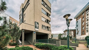 Um edifício moderno com formato triangular característico, várias varandas e uma placa indicando ser um empreendimento de apartamentos para clínicas médicas.