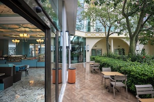 Pátio interno com piso de madeira, assentos externos e vista para o exterior através de portas de vidro.