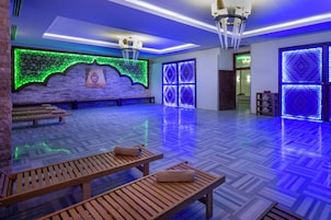 Um quarto espaçoso com bancos de madeira, parede de tijolos com iluminação LED verde e paredes com padrão azul.