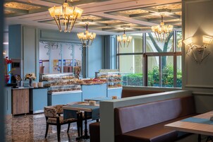 Um restaurante com interior azul, mobiliário de madeira e uma grande janela que oferece vista para o verde.