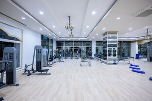 Uma academia moderna com diversos equipamentos de exercício, um caminho central para caminhada e um lustre.