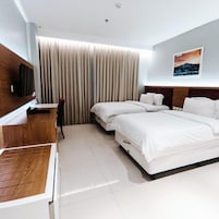 Quarto de hotel com cama, escrivaninha e televisão.