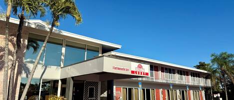 Um hotel moderno com a placa 'Garden Inn', uma área de recepção e um estacionamento com vagas demarcadas.