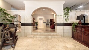 Um hall amplo com teto alto, um arco central e uma área de estar com um sofá vermelho.