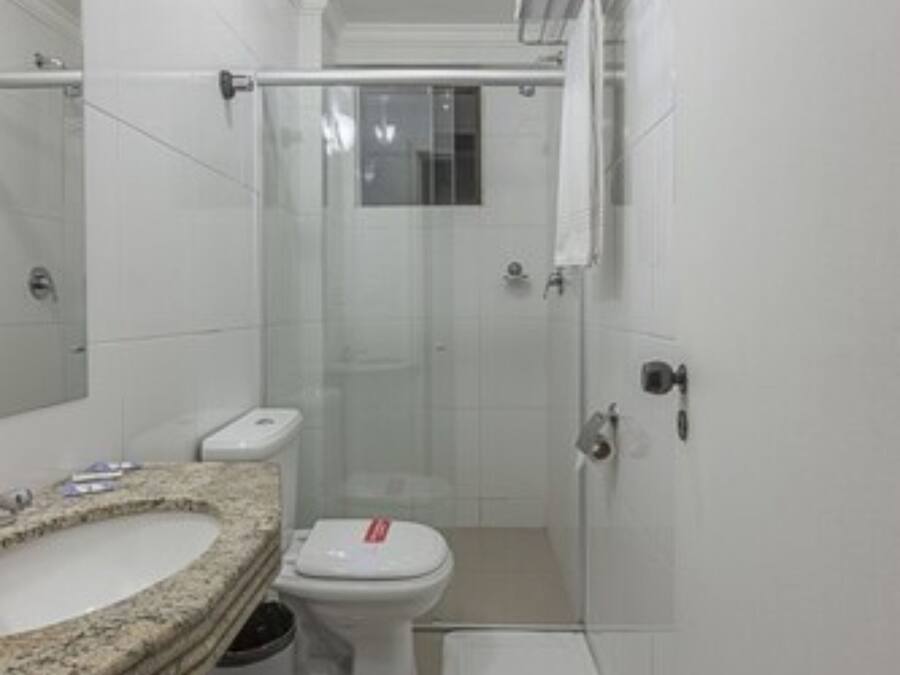 Uma casa de banho compacta com lavatório de granito, sanita branca e cabine de duche em vidro.