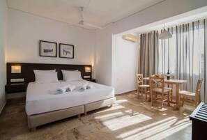 Quarto de hotel com uma cama, uma escrivaninha e uma cadeira. Dois quadros emoldurados na parede.