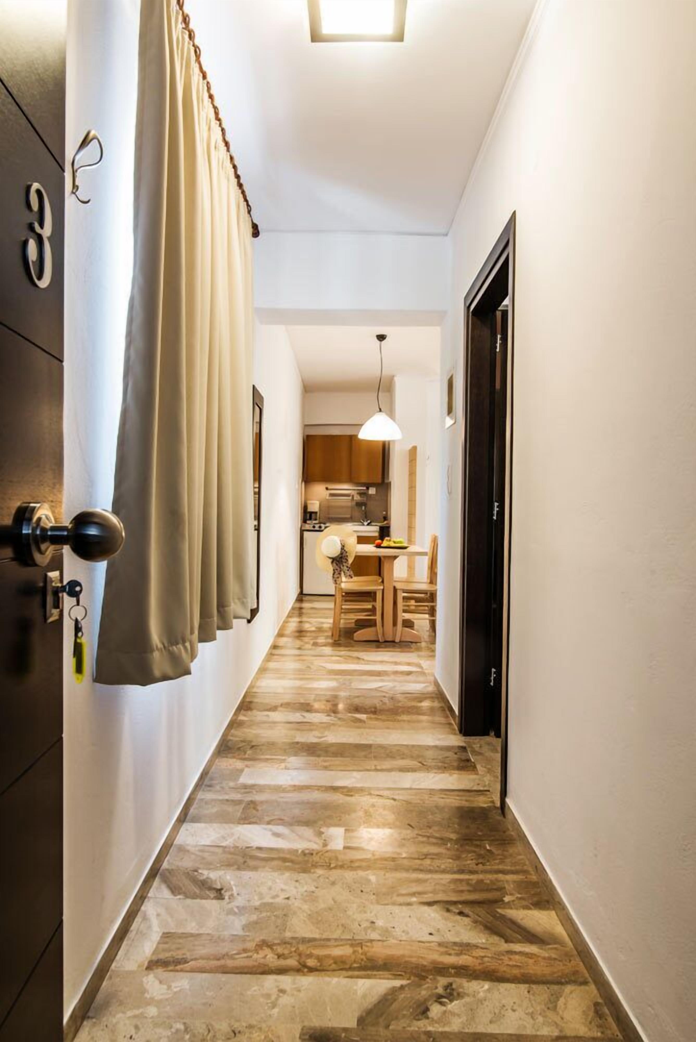 Um corredor com piso de madeira que leva a uma área de cozinha.