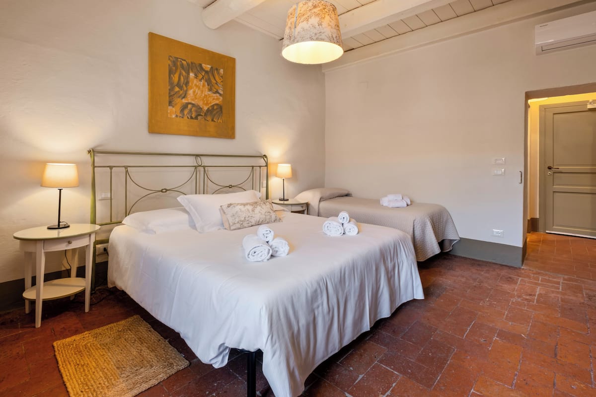 Quarto de hotel com duas camas, um quadro na parede, uma luminária e um tapete no chão.