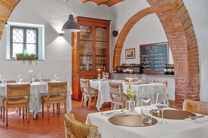 Interior de restaurante com arcos de tijolo, mobiliário de madeira e carta de vinhos na parede.