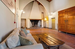 Uma sala de estar acolhedora com lareira, sofá, mesa de madeira e um armário grande de madeira.