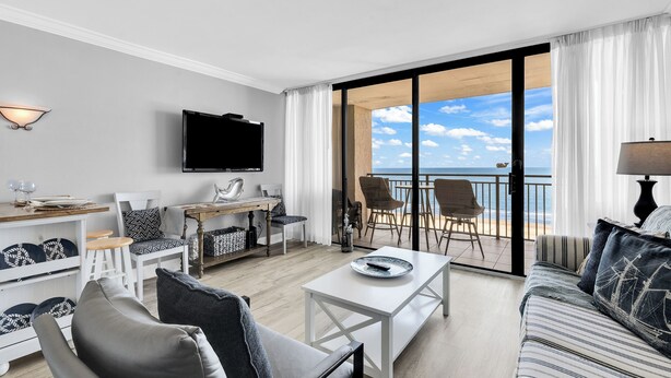 Quarto de hotel moderno com varanda, televisão de tela plana, área de refeições e sofá.