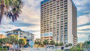 Um hotel moderno com vários sacadões, design arquitetônico contemporâneo e área circundante com palmeiras e uma placa com a inscrição 'The Grove'.