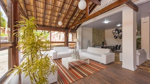 Uma sala de estar espaçosa com teto de madeira, sofás brancos, mesa de centro e tapete listrado.