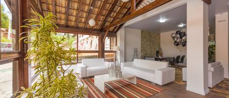 Uma sala de estar espaçosa com teto de madeira, sofás brancos, mesa de centro e tapete listrado.