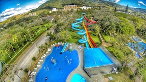 Um parque aquático com várias escorregas, uma piscina grande e áreas de descanso.