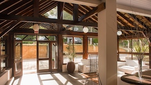 Uma sala de estar integrada com teto alto, janelas amplas e vista para o exterior.